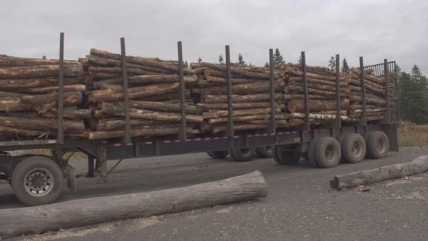 AERIAL CLOSE UP Flying along the timberjack harvester semi truck fully ...