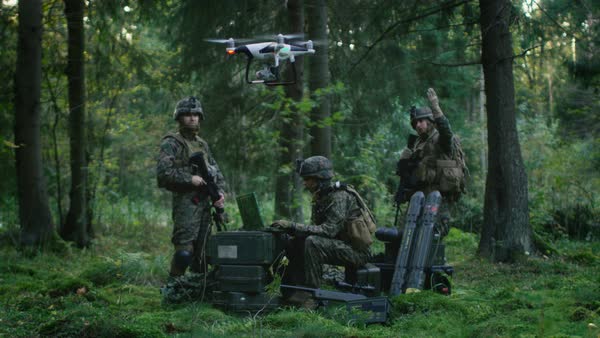 Military staging base, chief army engineer sitting on the boxes of ammunition uses army grade ...