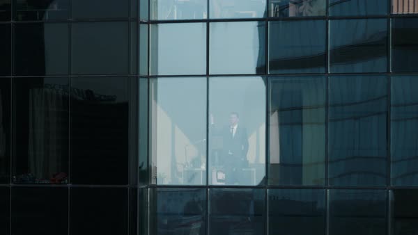 Aerial view footage: from outside into office building with businessman ...