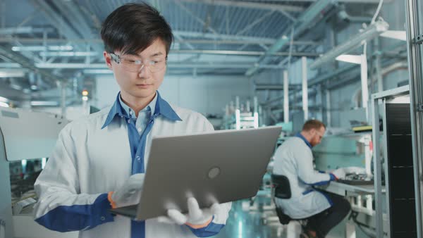 On High-Tech Factory Asian Engineer Uses Laptop Computer for ...