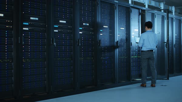 In a modern data center: IT engineer working with server racks, uses ...