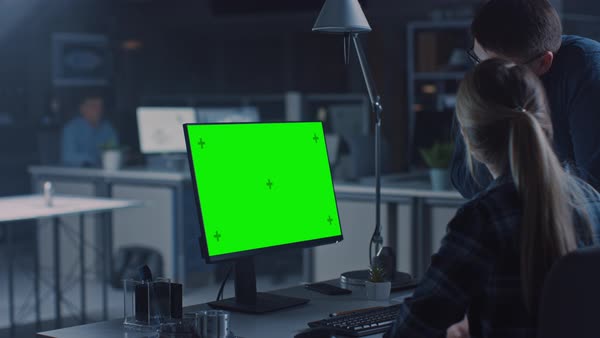 Engineer working on green screen desktop computer at night in ...