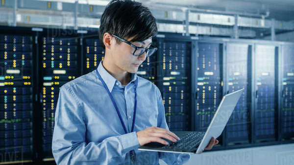 In the Modern Data Center: Portrait of IT Engineer Standing with Server ...