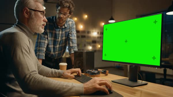 Middle aged man works on a desktop computer green screen and has ...