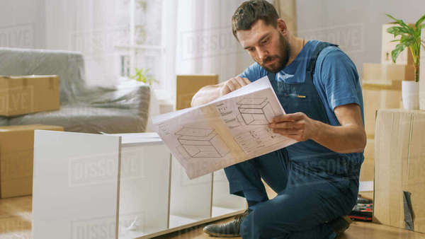 Successful furniture assembly worker reads instructions to assemble ...