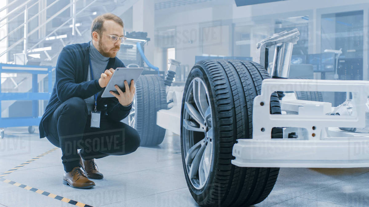 Engineer with Glasses and Beard Works on a Tablet Computer Next to an ...