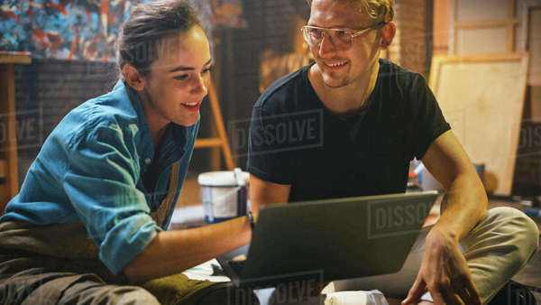 Couple of Artists Sitting in their Studio Use Laptop Computer, Working ...