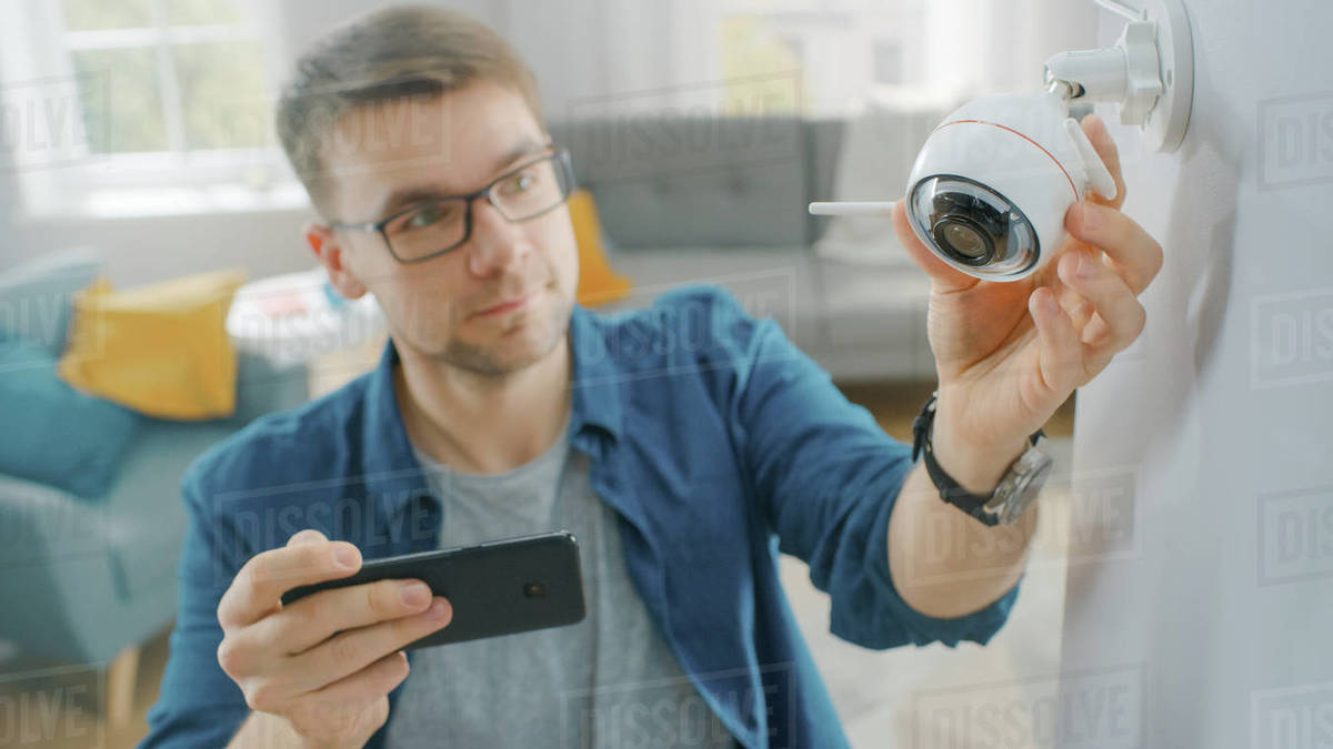Young Man in Glasses Wearing a Blue Shirt is Adjusting a Modern Wi-Fi ...