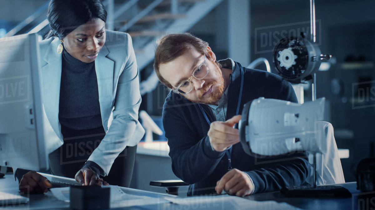 Electronics Development Engineer Working at His Desk, Talks with ...
