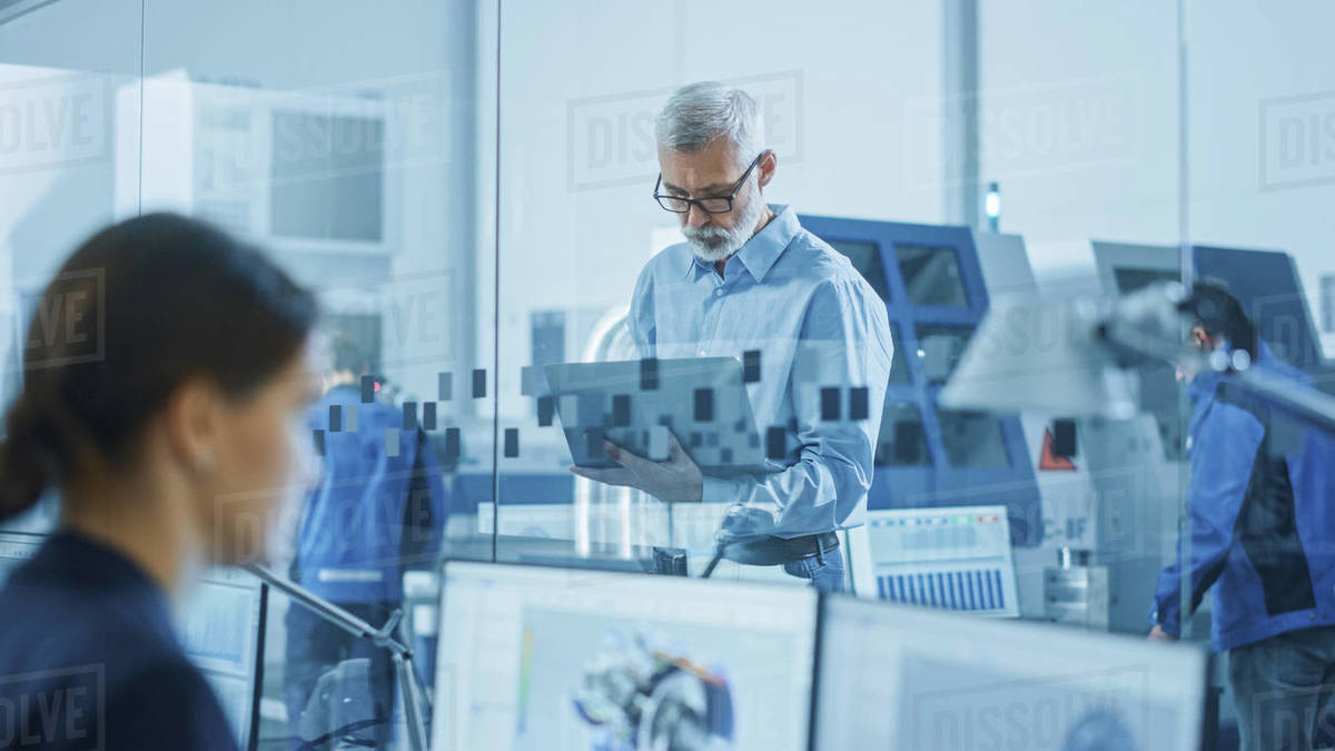 Modern Factory: Senior Engineer Looks at Camera, Holding Laptop ...