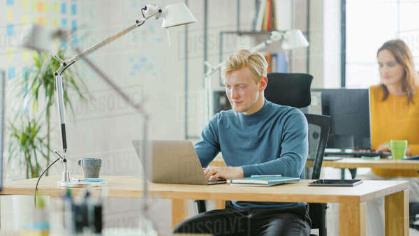 Handsome Caucasian IT Specialist Sitting at His Desk Works on a Laptop ...