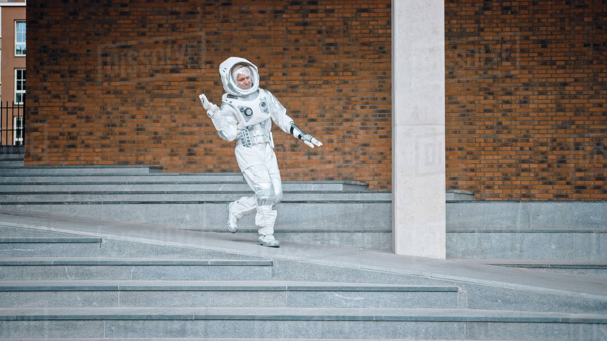 Handsome Man in Spacesuit is Dancing on Concrete Stairs. Astronaut is ...