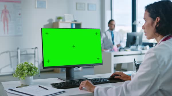 Female medical doctor working on a computer with green screen display ...