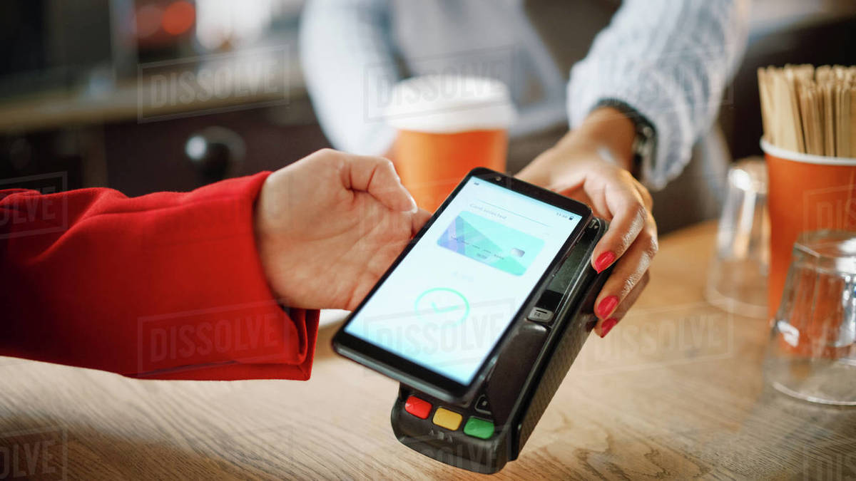 Close-up view of barista handing payment terminal to customer using a ...