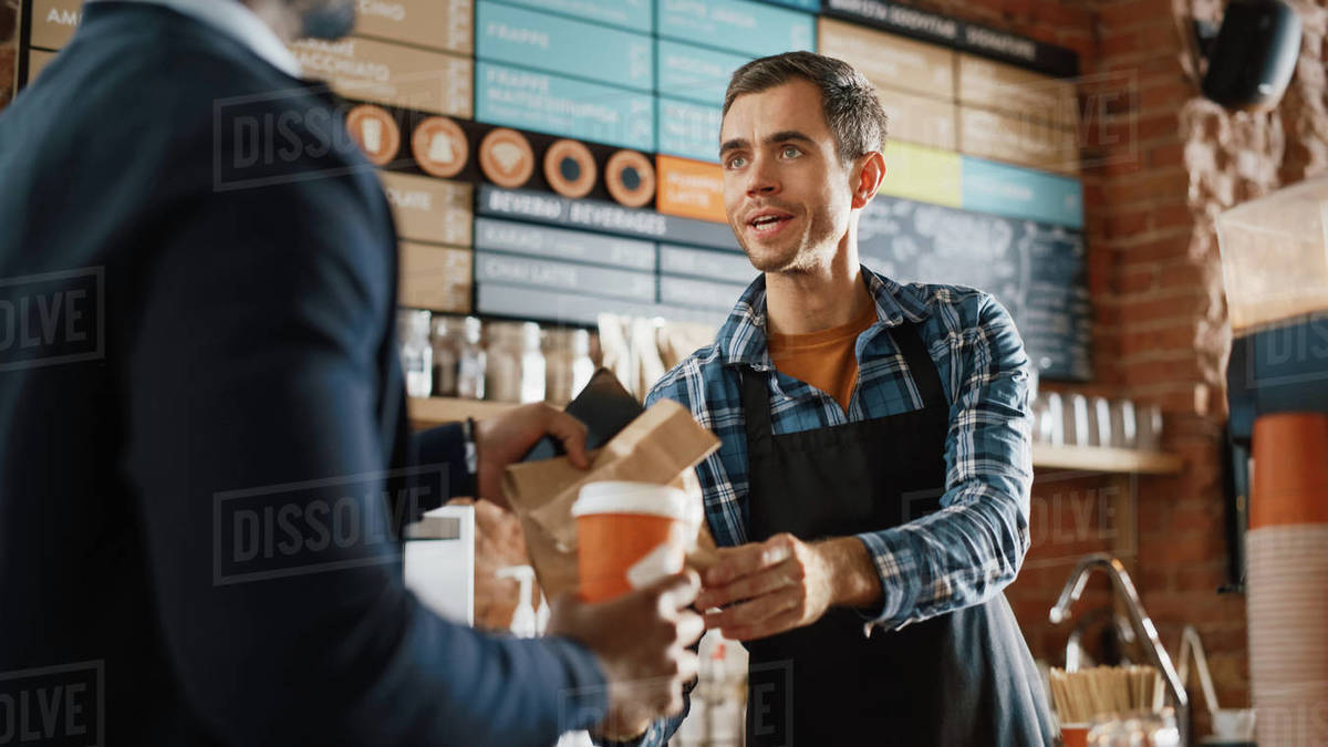 Close-up view of a barista handing order to a customer at a coffee shop ...