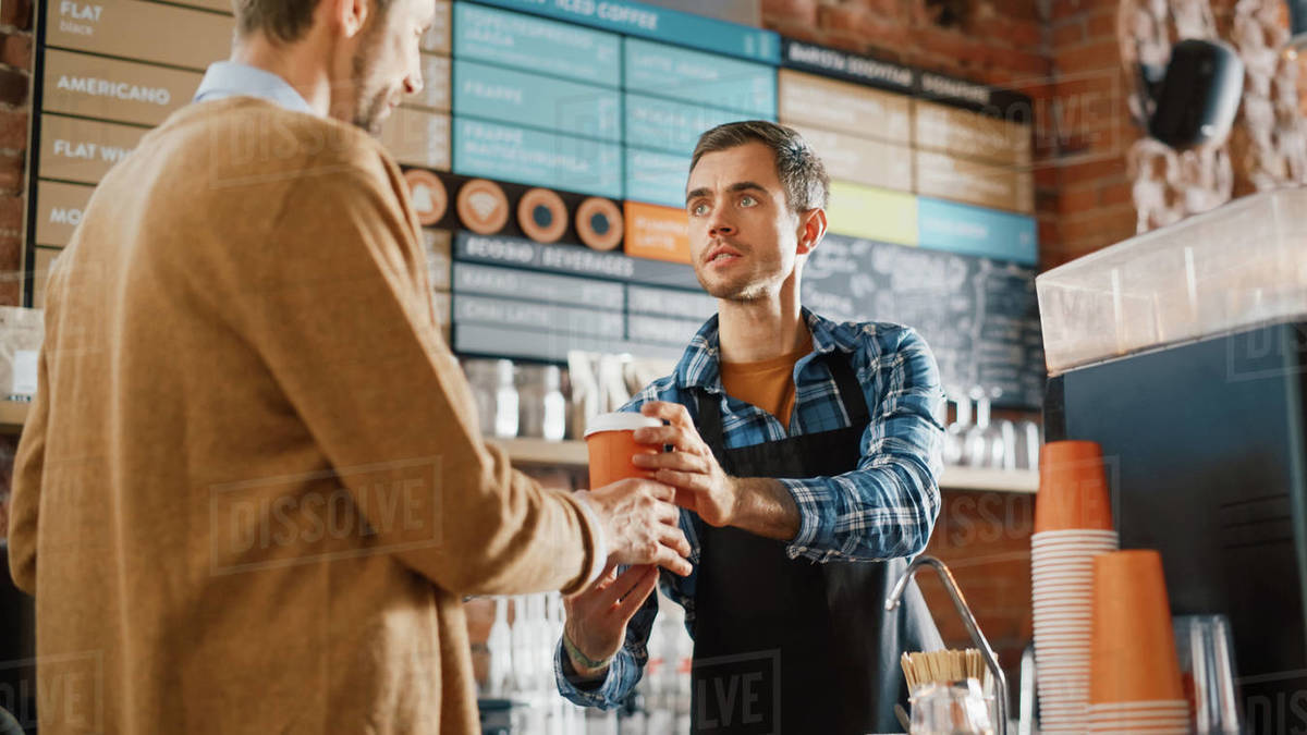 Close-up view of a barista handing over an order to a customer at a ...
