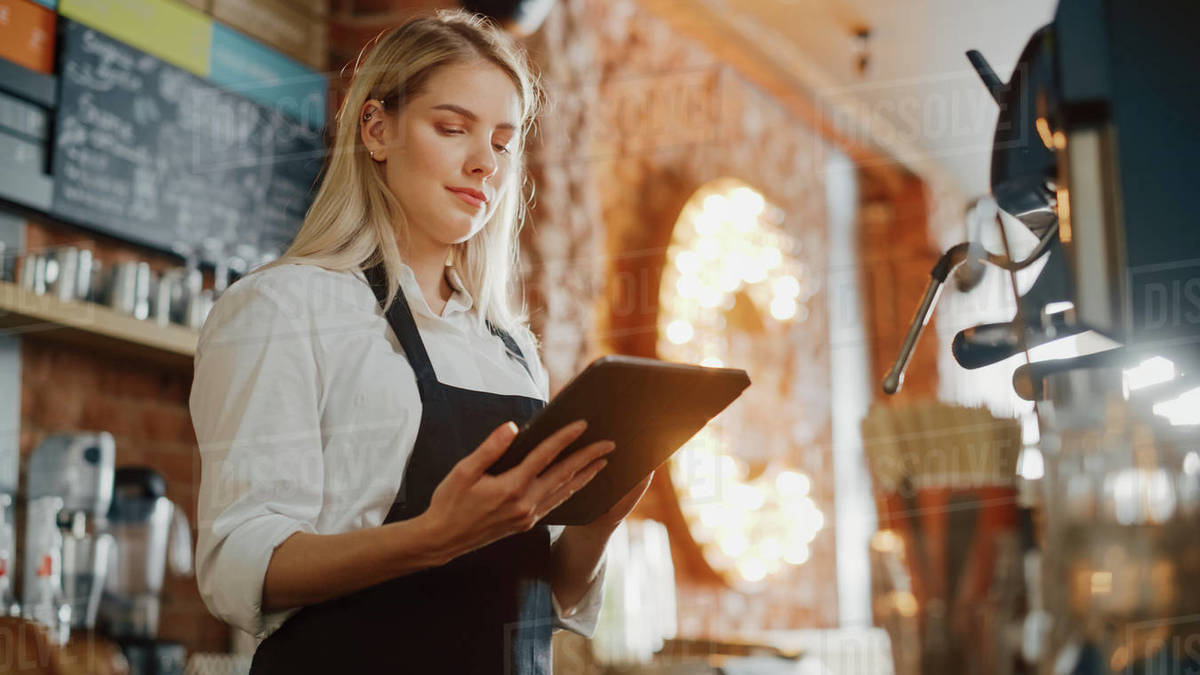 Female barista making notes and taking inventory on a tablet while ...