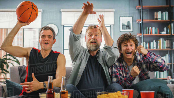 At Home Three Joyful Basketball Fans Sitting on a Couch Watch ...