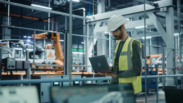Car Factory: Male Automotive Engineer Wearing Hard Hat, Standing, Using ...