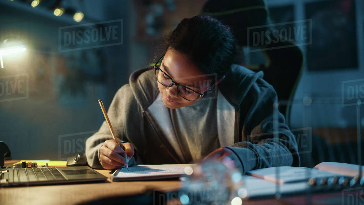 Young Teenage Black Girl Writing Down Homework in a Notebook with a ...