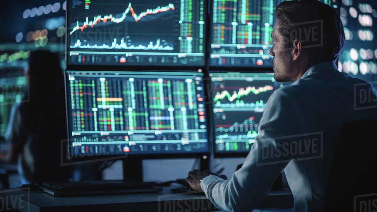 Financial Analyst Working on a Computer with Multi-Monitor Workstation ...