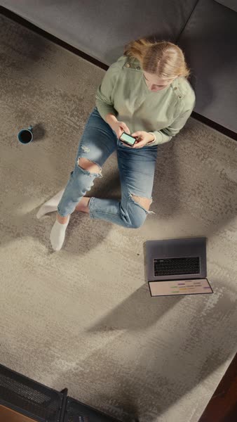 Vertical Screen Apartment: Woman Uses Smartphone Sitting on carpet in ...