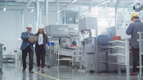 Two Diverse Heavy Industry Engineers in Hard Hats Walking with Laptop ...