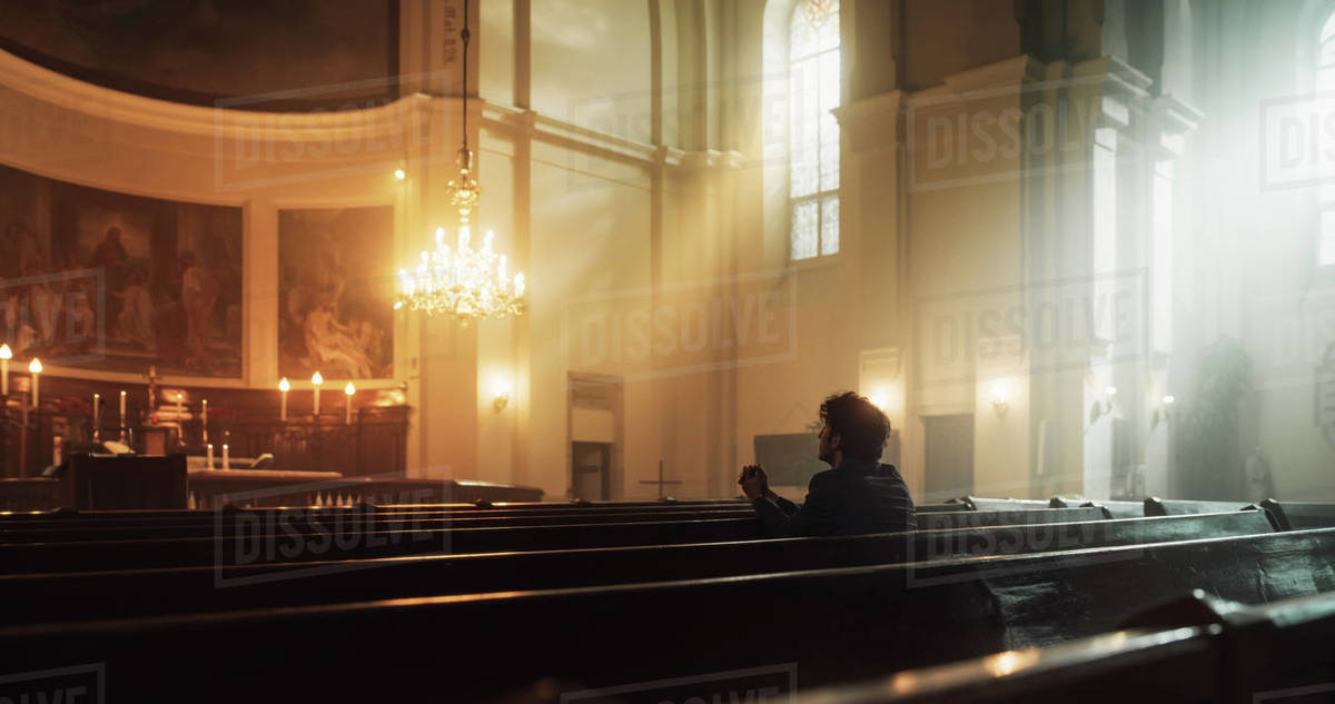 A Devout Christian Sits Piously In A Grand Church, Folding Hands For ...