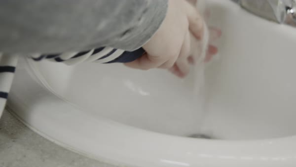 Reflection in bathroom mirror of mother helping son washing hands ...
