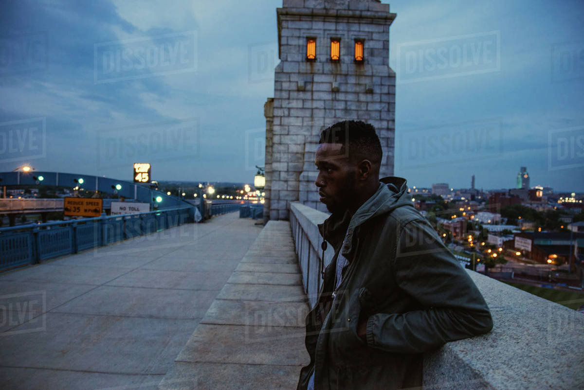Man standing on bridge at dusk - Royalty-free Stock Photo | Dissolve