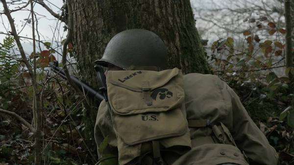 Reenactment of WW2 American infantry soldier peaks out behinde tree ...