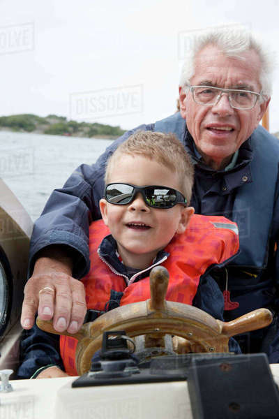 Boy driving boat with grandfather - Stock Photo - Dissolve