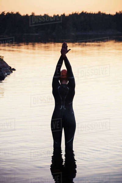 Swimmer standing in water at sunset - Royalty-free Stock Photo | Dissolve