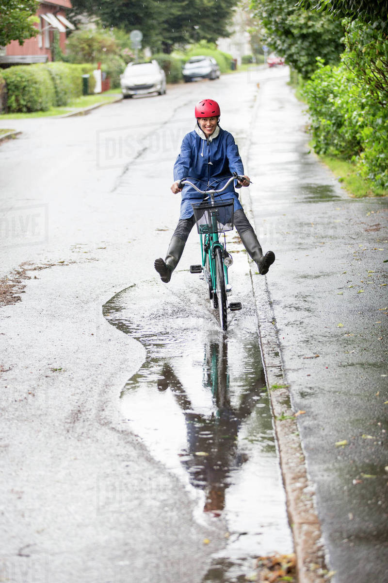 Woman riding bicycle through puddle - Royalty-free Stock Photo | Dissolve