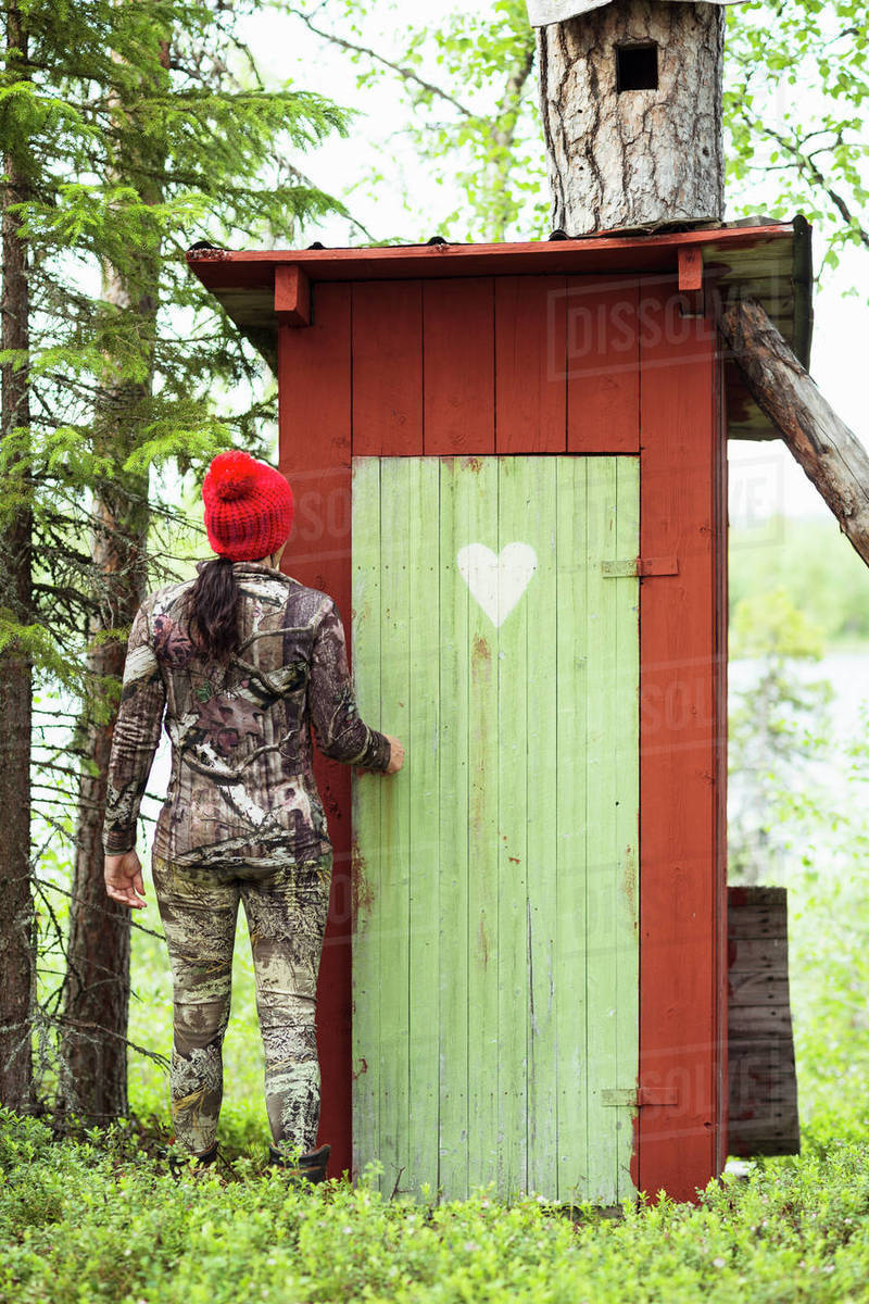 Woman entering wooden outhouse - Royalty-free Stock Photo | Dissolve