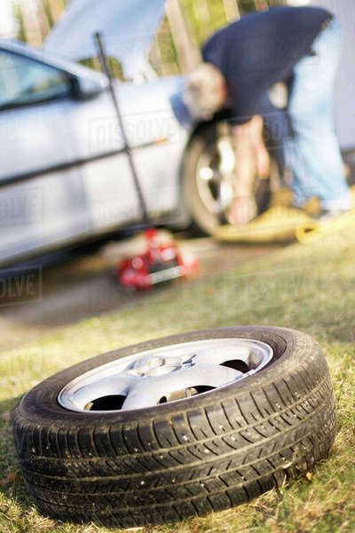 Man changing tire, spare wheel on foreground - Royalty-free Stock Photo ...