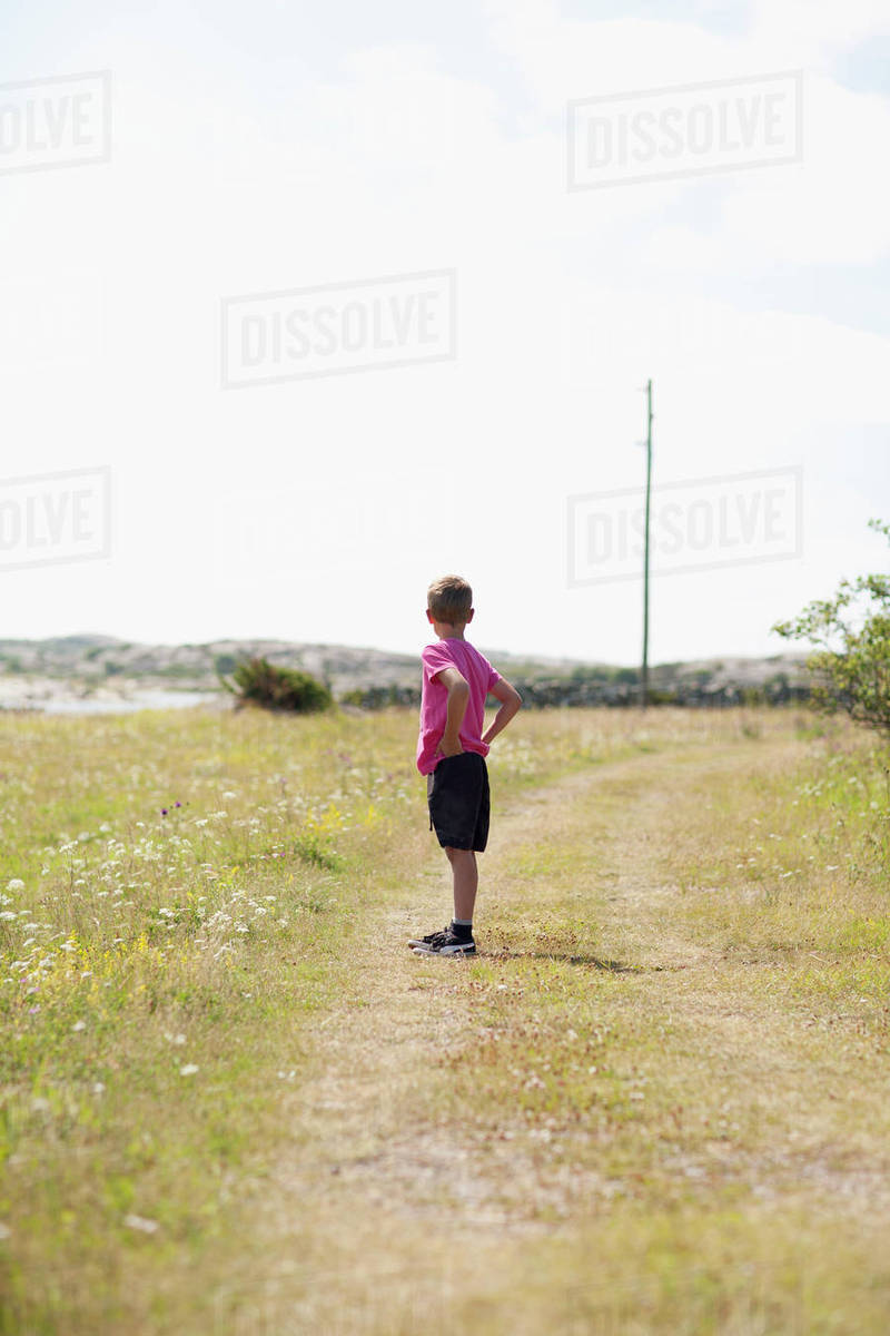 Boy standing on dirt road - Royalty-free Stock Photo | Dissolve