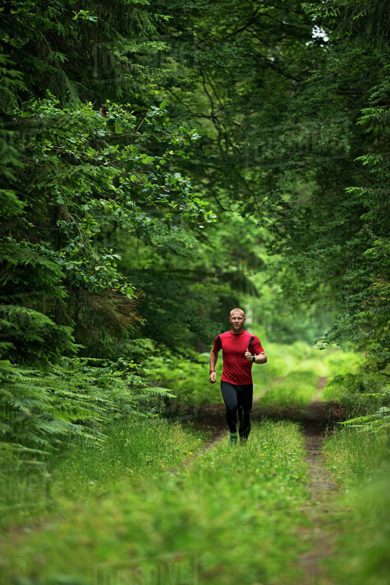 Young man running through forest - Royalty-free Stock Photo | Dissolve