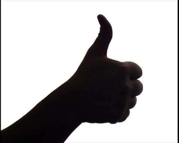 Close up up of a hand flashing a thumbs up sign silhouetted against ...