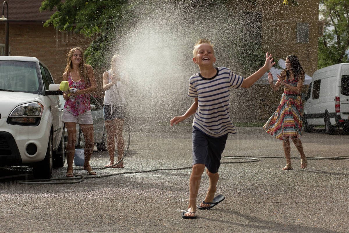 Happy children playing in spraying water hose in driveway - Royalty ...