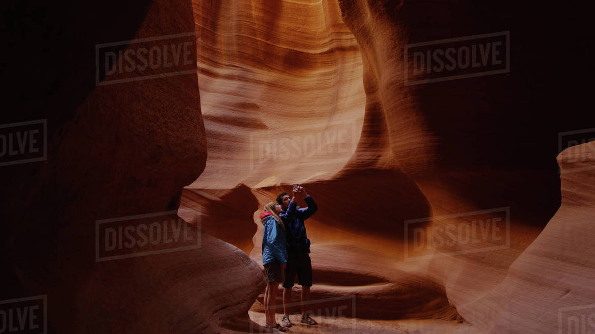 Hiking couple photographing majestic grooved rock formation caves ...