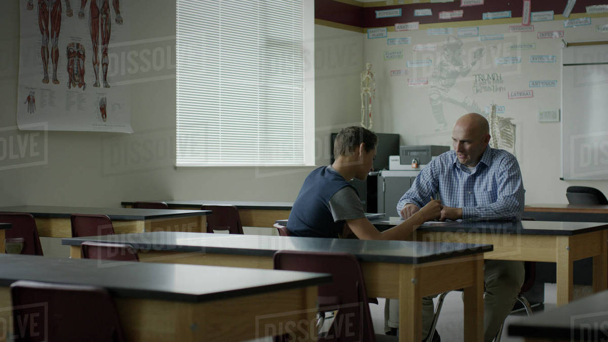 Teacher instructing and tutoring student in classroom - Royalty-free ...