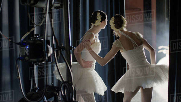 Serious ballet dancers in costume watching performance backstage during ...