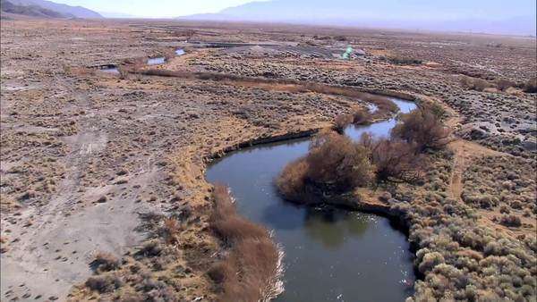 Mountain range in the middle of a desolate desert. Small river runs ...