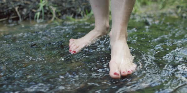 Barefoot woman with red nails wading in shallow river rapids - 4K ...