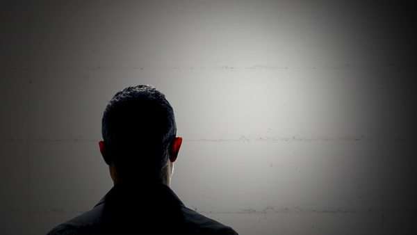 Witness criminal being interviewed in a dark room silhouette back view ...