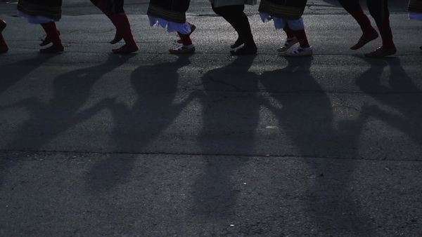 Kolo - people dancing Serbian folk dance, focus on legs and shadows on ...