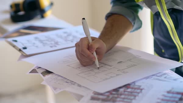 Experienced architect correcting interior project drawings of apartment ...