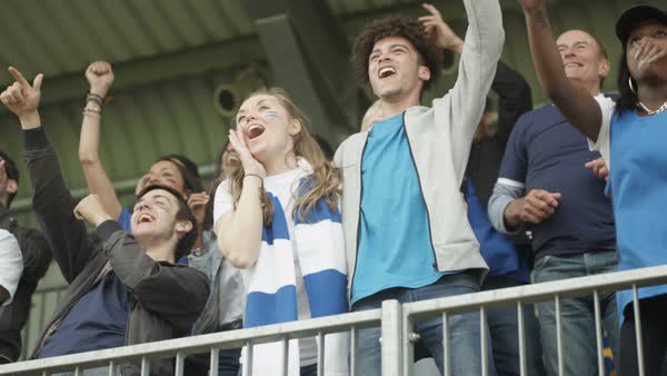 Excited sports fans at live event clapping & cheering for their team ...