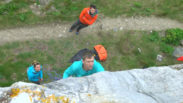 Group of climbers beginning a climb on rocky cliff face - Stock Video ...